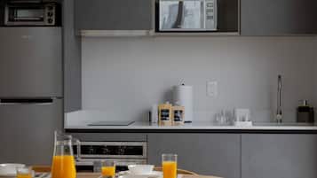 Cozinha moderna equipada com micro-ondas embutido, forno elétrico e geladeira de aço inoxidável.