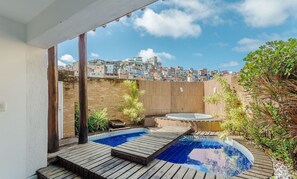 Piscina no terraço com deck de madeira e vista para um horizonte urbano congestionado.