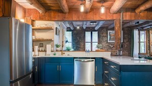 Cozinha com vigas de madeira, geladeira de aço inoxidável e lava-louças.