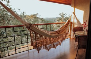 Uma rede em uma varanda com vista para uma paisagem montanhosa.