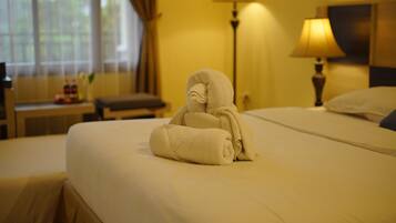 Quarto de hotel com duas camas, uma mesa de cabeceira com abajur e uma janela com cortinas.
