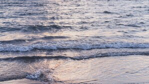Uma praia com ondas batendo suavemente na costa.