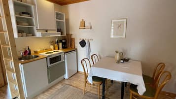 Cozinha compacta com área de refeições, armários de madeira, fogão e mesa posta para dois.