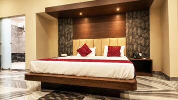 Quarto de hotel moderno com uma cama grande, cabeceira de madeira, piso de mármore e um banco embutido.