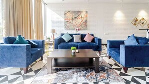 Uma sala de estar moderna com um sofá azul, uma mesa de centro e um tapete estampado.