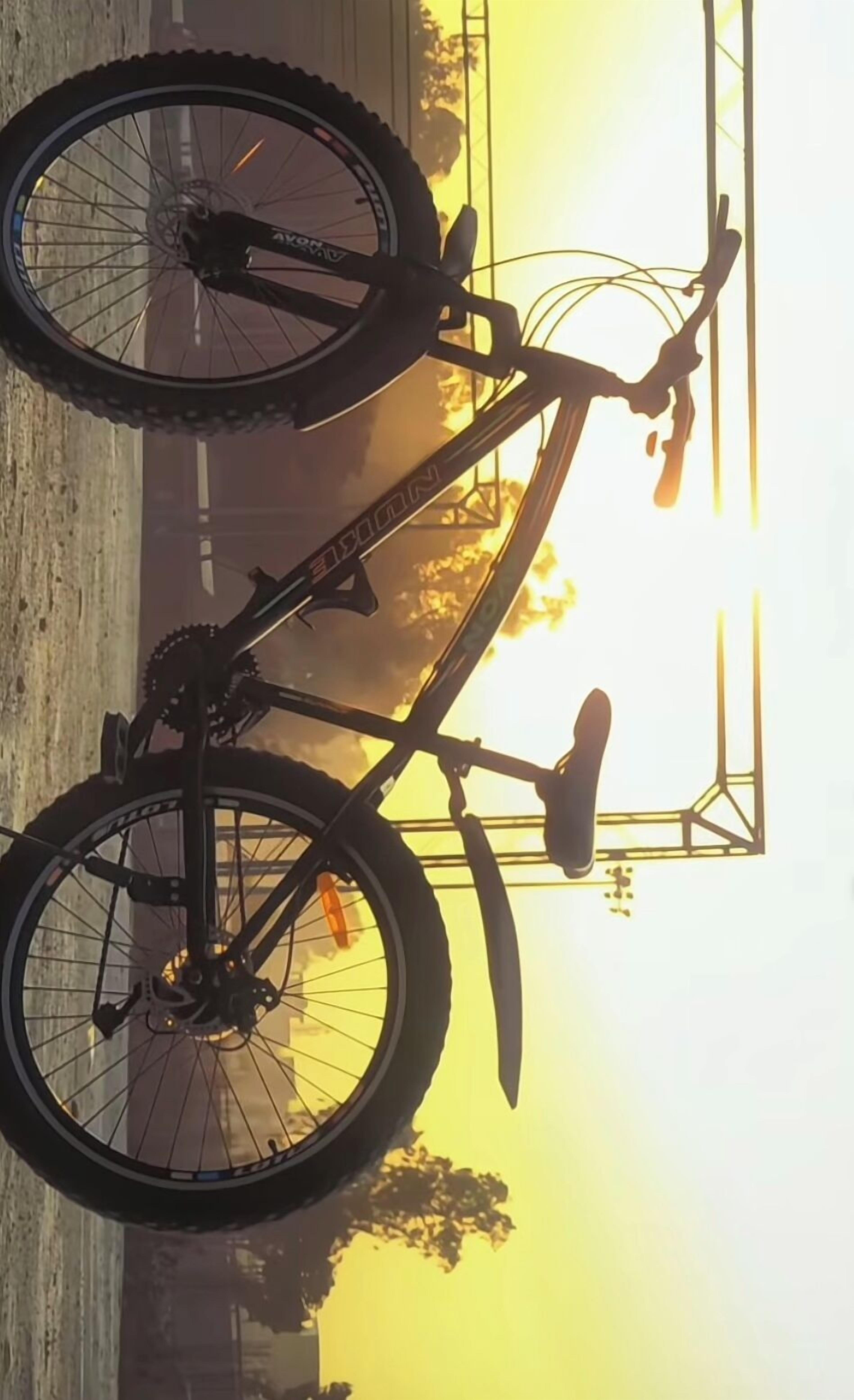 Uma bicicleta encostada a uma parede, com o pôr do sol ao fundo.