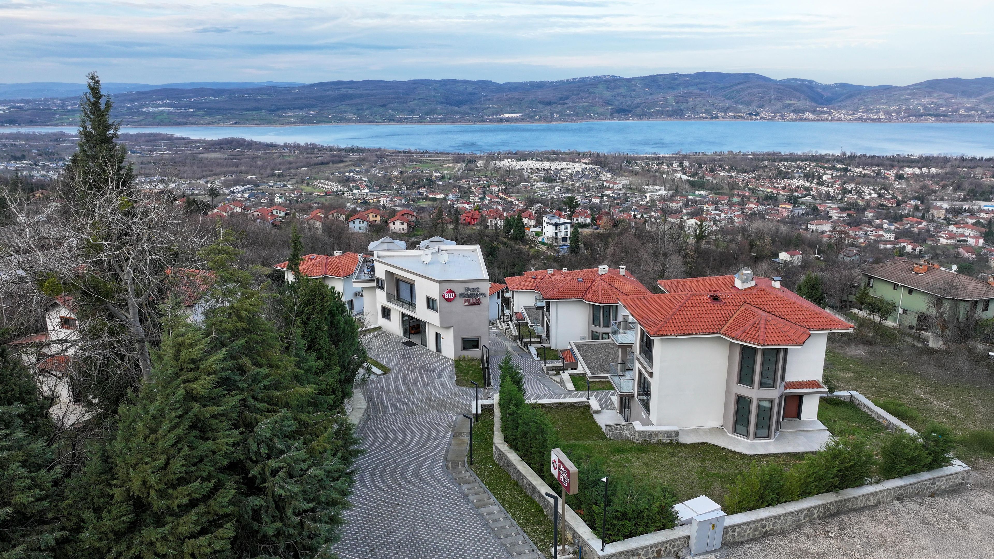 Zona residencial com casas modernas, vista clara de um lago e paisagem montanhosa ao fundo.