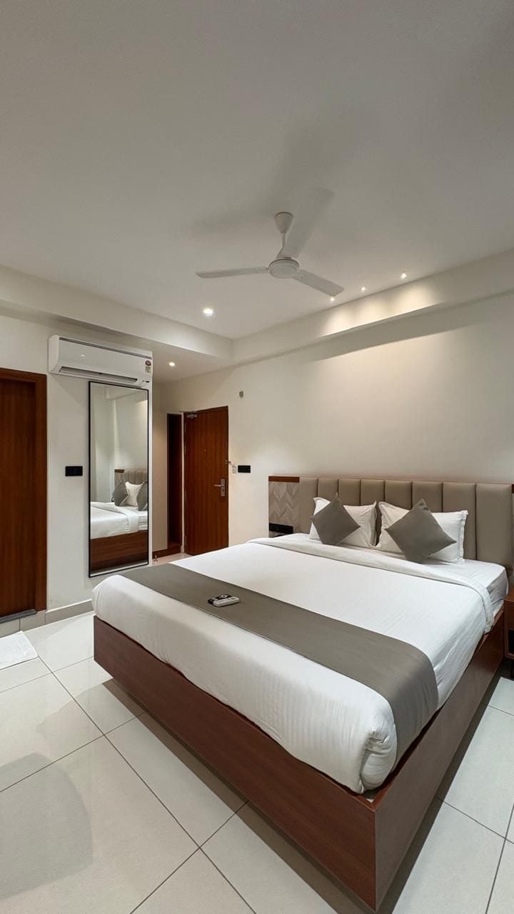 Quarto de hotel moderno com uma cama grande, ventoinha de teto e espelho.