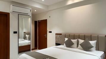 Quarto de hotel moderno com uma cama grande, ventoinha de teto e espelho.