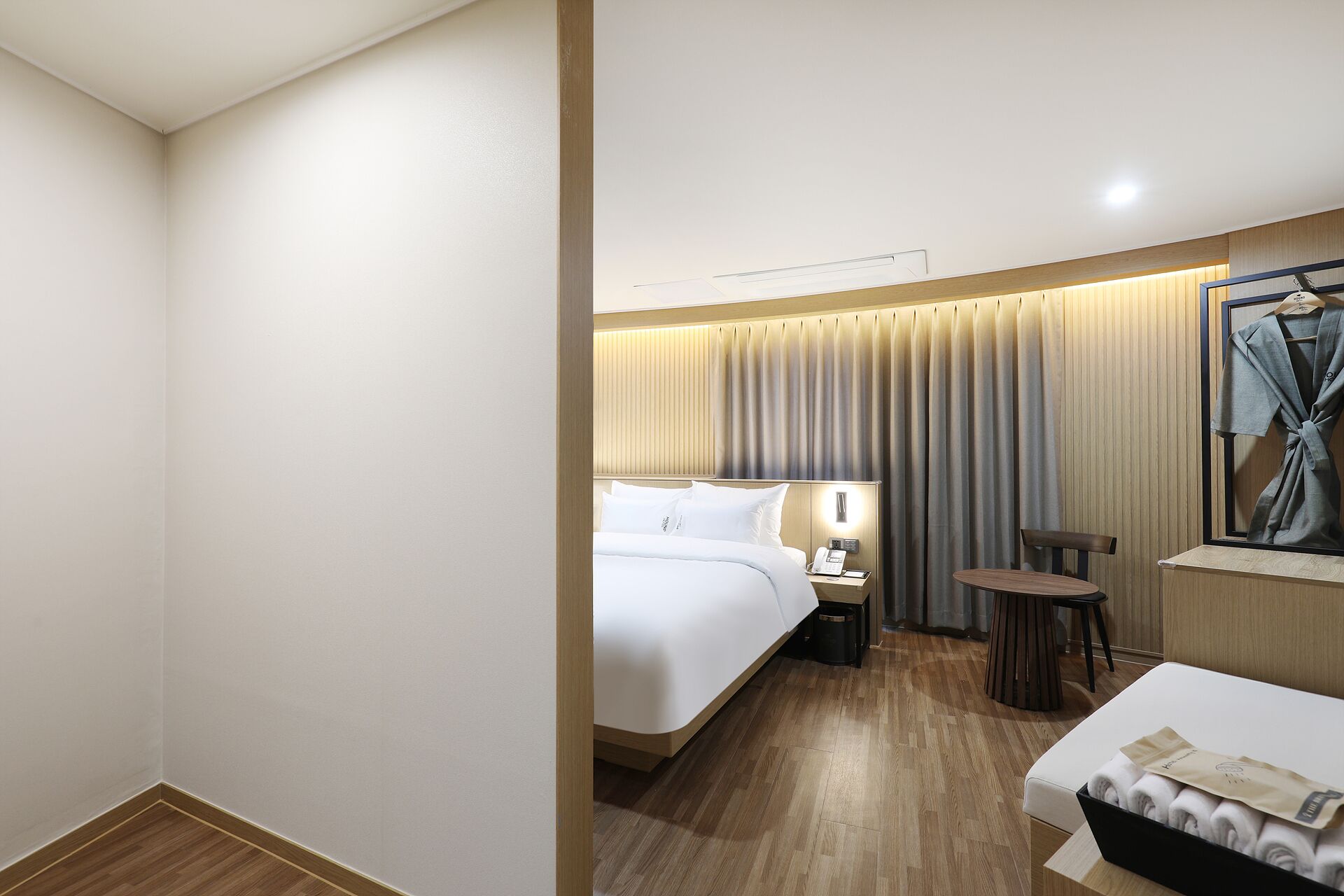 Quarto de hotel moderno com uma cama grande, mesas de cabeceira, uma escrivaninha e uma cadeira.