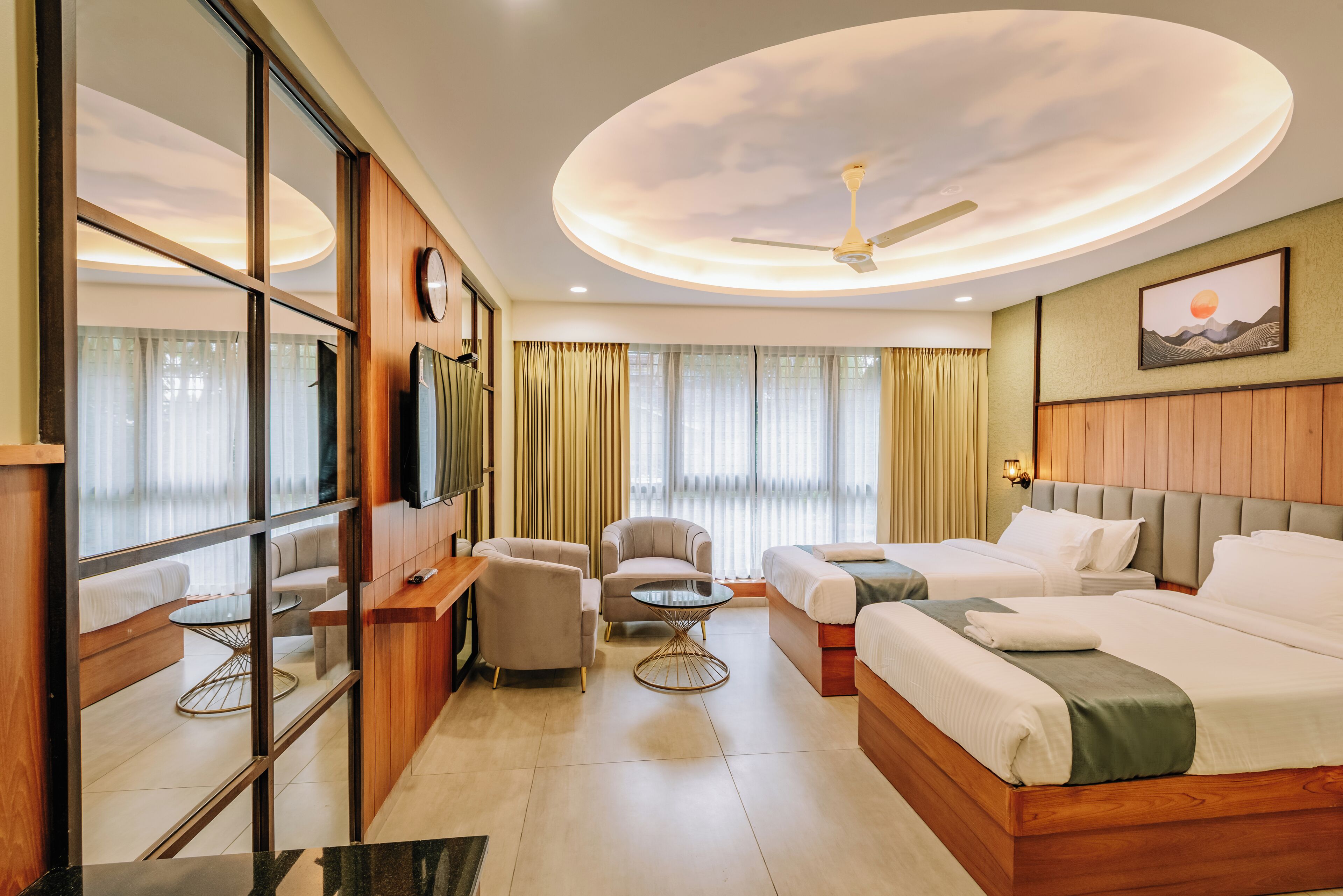 Quarto de hotel com duas camas, um sofá, uma cadeira, uma televisão e um ventilador de teto.