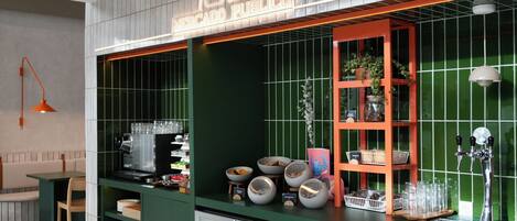 Um espaço de bar moderno com um letreiro de neon, paredes revestidas de azulejos verdes e diversos copos e tigelas sobre o balcão.