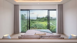 Quarto com uma grande janela, uma cama e duas luminárias laterais.