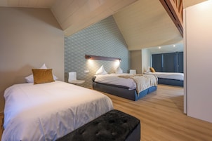 Um quarto moderno com duas camas, um banco e um design de teto único.