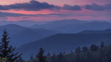 Paisagem montanhosa com florestas densas e céu claro.