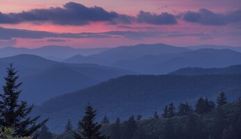 Paisagem montanhosa com florestas densas e céu claro.