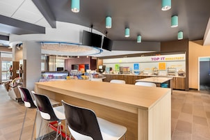Uma área de café da manhã moderna com balcão, assentos e um aviso com a inscrição 'TOP IT BREAKFAST'.