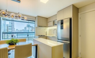 Uma cozinha moderna com geladeira embutida, fogão a gás e uma janela grande com vista para a cidade.