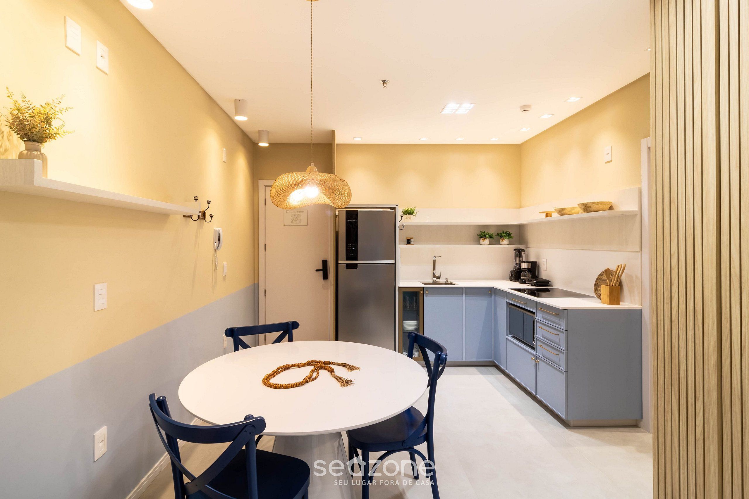 Cozinha moderna com mesa de jantar redonda, cadeiras e luminária pendente.