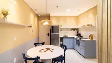 Cozinha moderna com mesa de jantar redonda, cadeiras e luminária pendente.