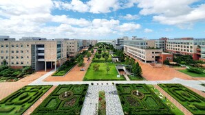 Um campus moderno com edifícios retangulares, gramados verdes e jardins com design geométrico.
