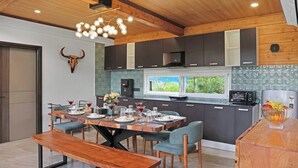 Cozinha moderna com armários de madeira, área de jantar com mesa e bancos de madeira, e decoração de crânio de touro na parede.