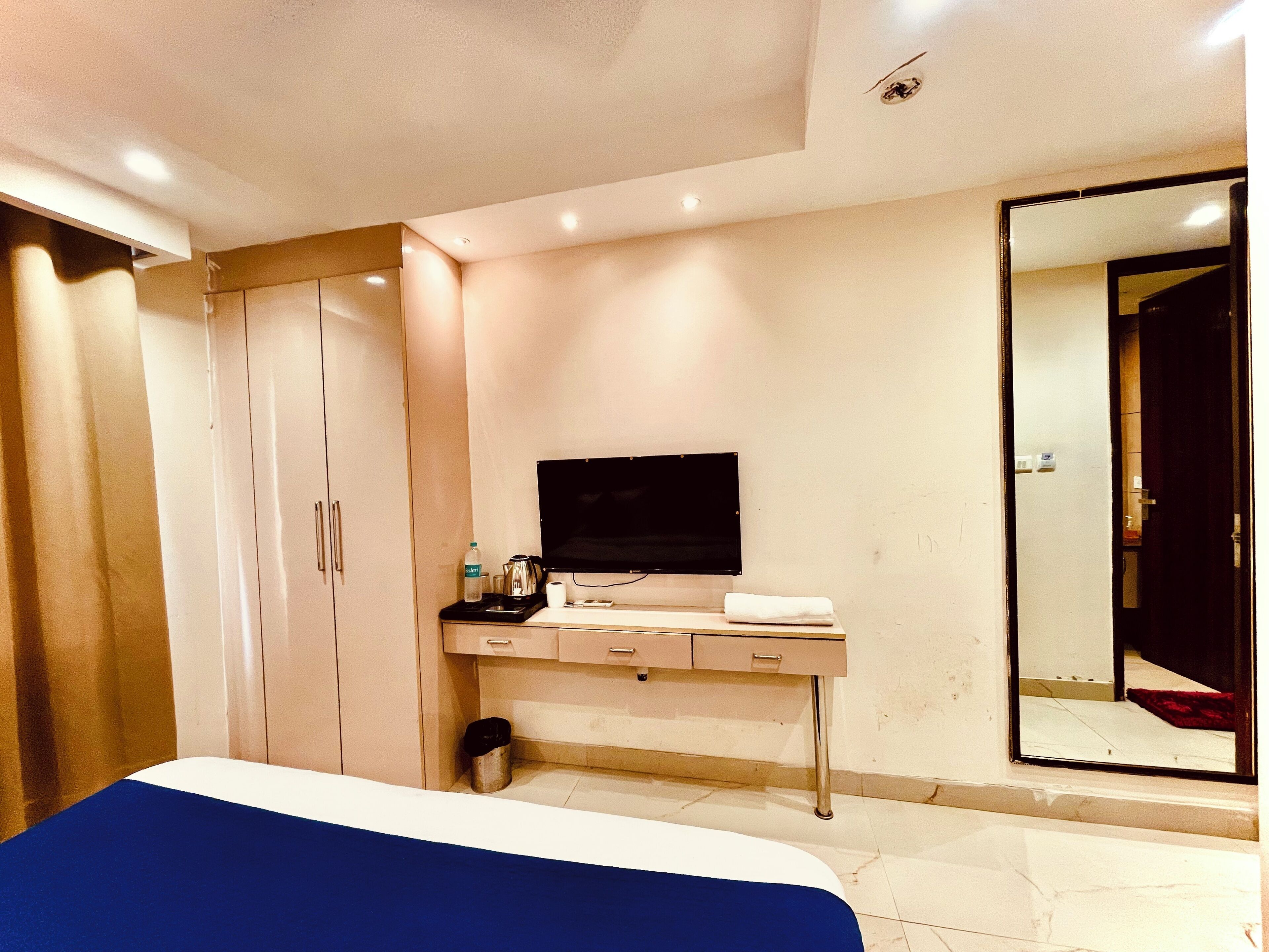 Quarto com cama, escrivaninha, televisão e guarda-roupa.