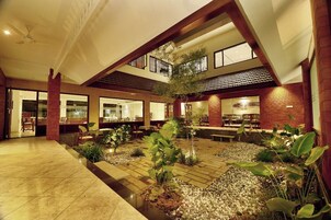 Um pátio interno espaçoso com área de estar central, rodeado por paredes de tijolo e grandes janelas.