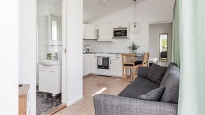 Uma cozinha moderna com armários brancos, micro-ondas e um espaço de refeições com mesa e cadeiras de madeira.