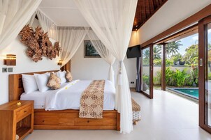 Quarto com cama grande, mesa de cabeceira e vista para uma piscina.