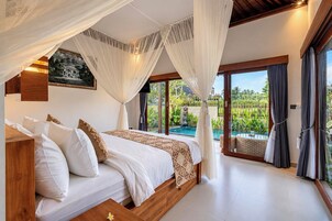 Quarto com cama, mesa de cabeceira, quadro e vista para uma piscina.