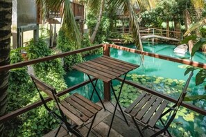Um deck de madeira com mesa e cadeiras, com vista para uma piscina com folhas de nenúfar.