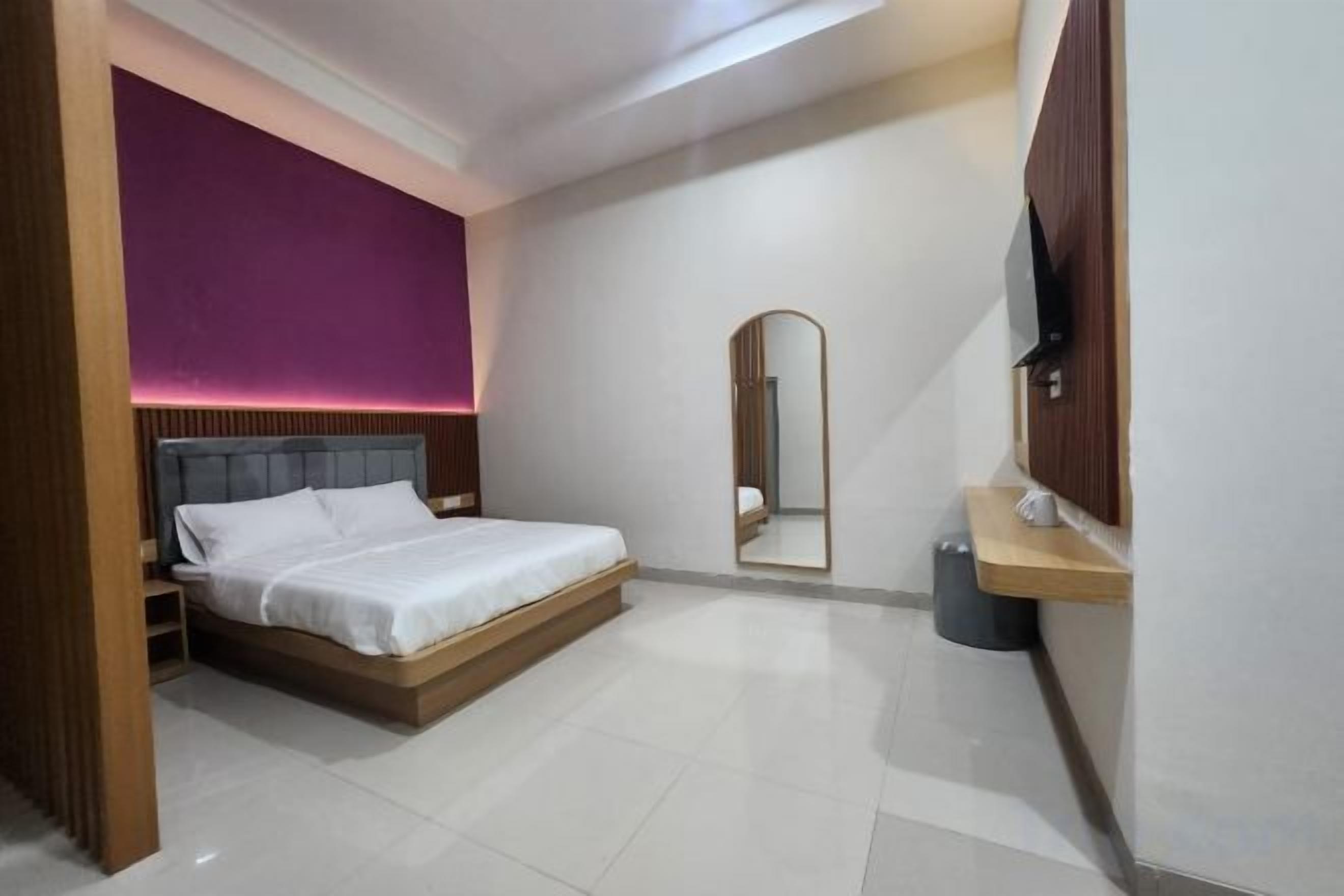 Quarto moderno com cama, mesa de cabeceira, espelho e pequena estante.
