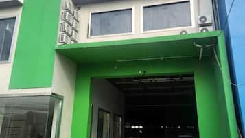 Entrada de prédio com toldo verde e porta de garagem.