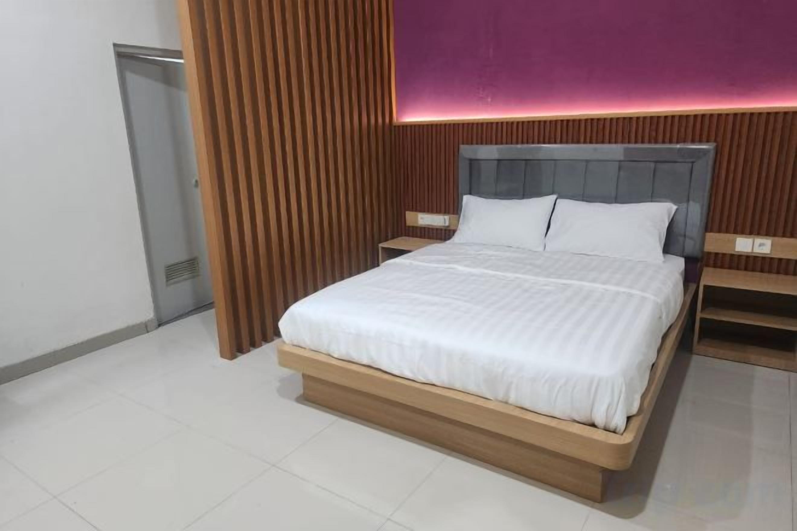 Quarto moderno com estrutura de cama de madeira, mesa de cabeceira e painel de cabeceira embutido.