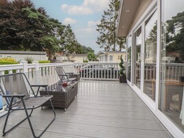 Um deck externo coberto com móveis de vime e uma porta de vidro que dá para uma área coberta.