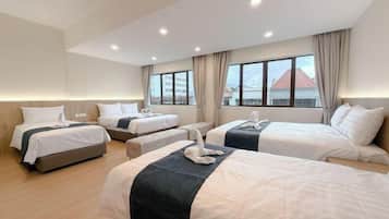 Quarto de hotel com três camas, uma janela grande e vista para a cidade.