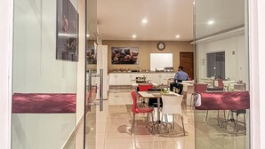 Cozinha moderna com armários brancos, uma ilha central e um espaço de refeições com cadeiras vermelhas.