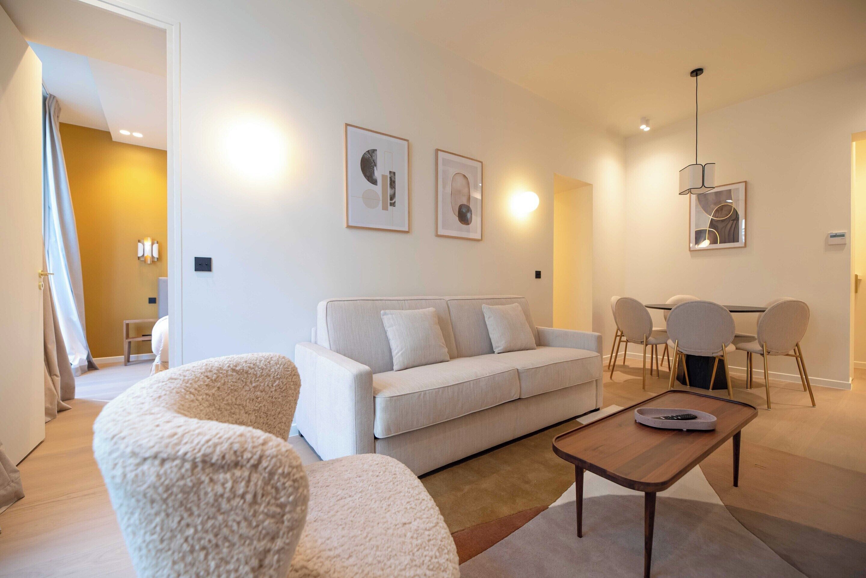 Uma sala de estar moderna com sofá, poltronas, uma mesa de jantar e obras de arte nas paredes.
