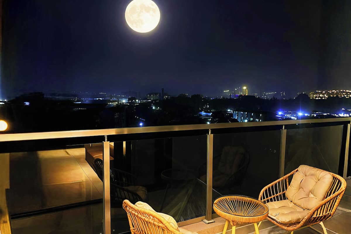 Varanda com duas cadeiras de vime e vista para a cidade à noite.