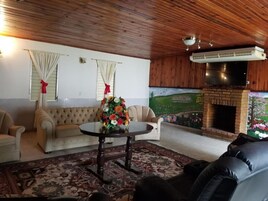 Uma sala de estar aconchegante com um sofá, uma mesa redonda com um arranjo floral e uma lareira.