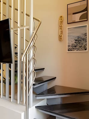 Uma escadaria moderna com guarda-corpo de metal e piso plano e escuro.