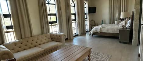 Um quarto espaçoso com uma cama grande, um sofá e uma mesa de centro de madeira.