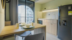 Cozinha moderna com geladeira embutida, mesa de jantar com cadeiras e janela com cortinas.