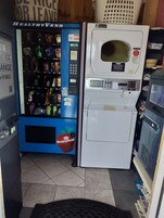Máquina de vendas automática e micro-ondas numa divisão com soalho em azulejos.