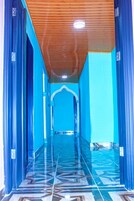 Um corredor com paredes azuis e chão estampado, que leva a uma porta com teto de madeira.