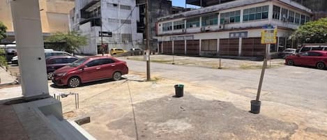Um estacionamento com um carro vermelho, um edifício em construção e uma placa.