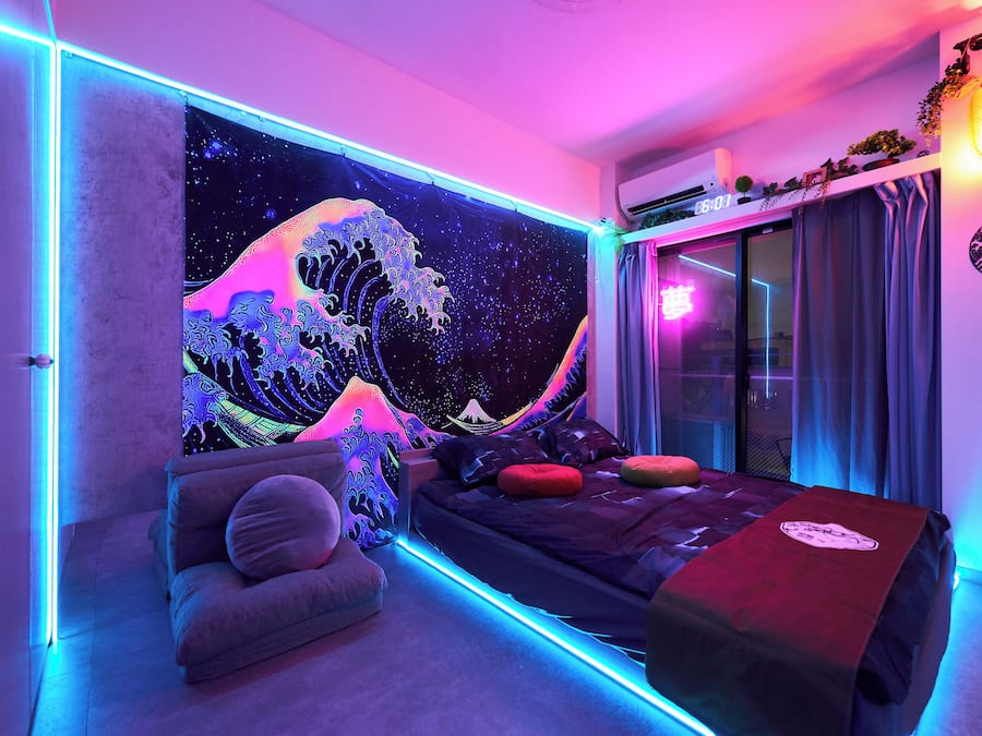 Um quarto com uma cama, uma cadeira, tapeçaria na parede e uma janela com cortinas.