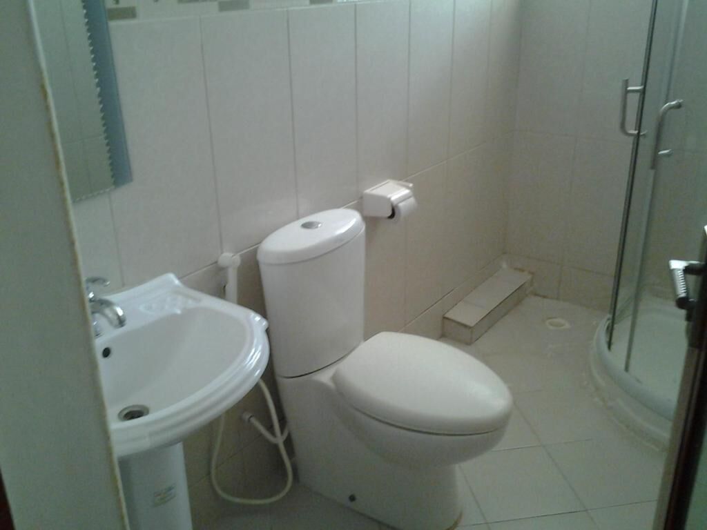 Um banheiro pequeno com vaso sanitário, pia e chuveiro.