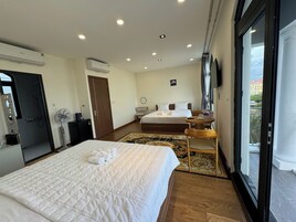 Quarto de hotel com duas camas, área de estar, janela grande e varanda.